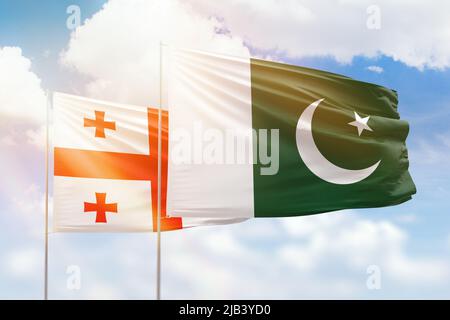 Pakistan and Georgia flags waving together on blue cloudy sky, two ...