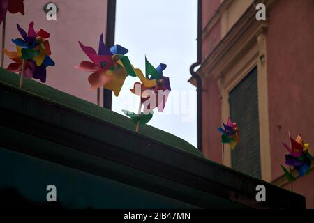 Pinwheels on a roof with two buildings in the backdrop on a rainy day ...