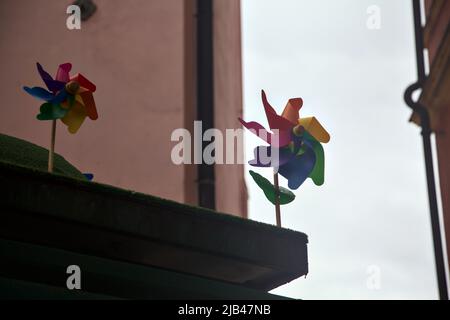 Pinwheels on a roof with two buildings in the backdrop on a rainy day ...