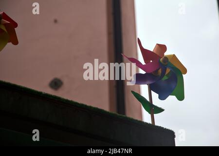 Pinwheels on a roof with two buildings in the backdrop on a rainy day ...
