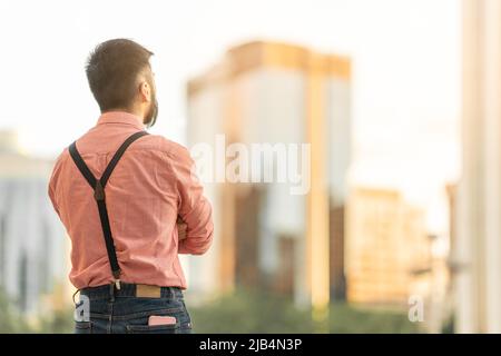 Asian man silhouette looking at sunset under a palm tree on the beach ...