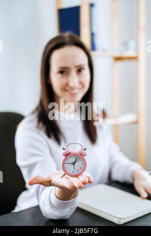 Woman in office points to alarm clock in her hand Stock Photo - Alamy