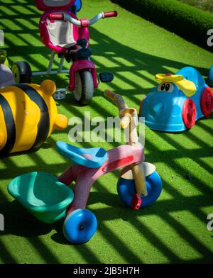 Children's colorful ride-on toys scattered on vibrant green grass in a ...