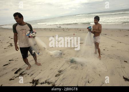 Fishermen organizing fishing nets on Kalala beach in Wula, Wula Waijelu ...