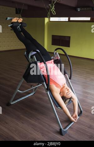A woman doing inversion therapy hanging upside down on an inversion ...