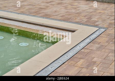 swimming pool drainage system grating covered with round white river ...