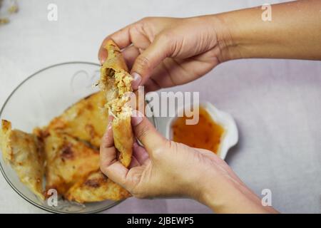 Woman hand holding Samosa with sauce on white tablecloth Stock Photo ...