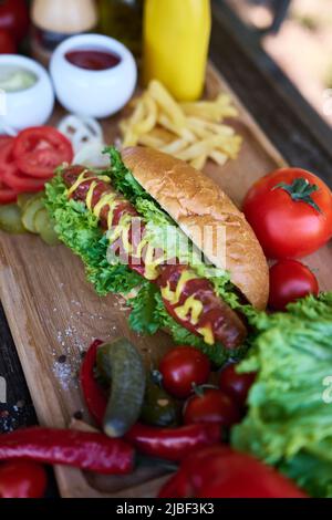 BBQ hot dog served with vegetables and French fries and sauces on ...