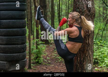 Woman practising kickboxing performing a leg axe kick working out ...