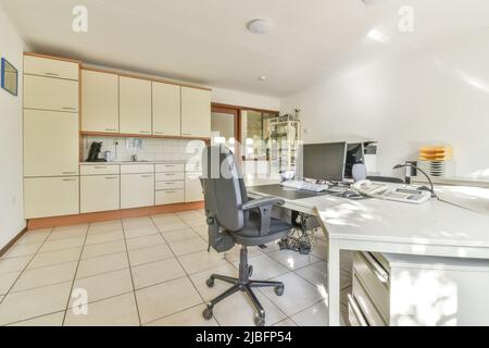 Tables with modern computers and printers in spacious office with ...