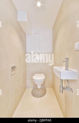 White ceramic toilet placed at white tiled wall in light stylish ...