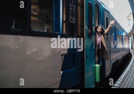 Woman with suitcase getting off passenger train at train station Stock ...