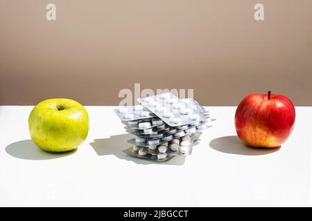 Apples and pills or vitamin capsules on white table, copy space ...