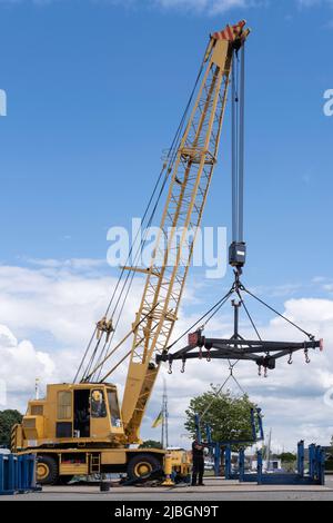 A construction worker guides a steel beam as it is lifted for the ...