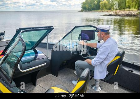 A man in a captains cap getting the boat ready Stock Photo - Alamy