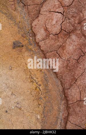 Closeup photograph of colorful dried earth in shades of gold, red, and ...