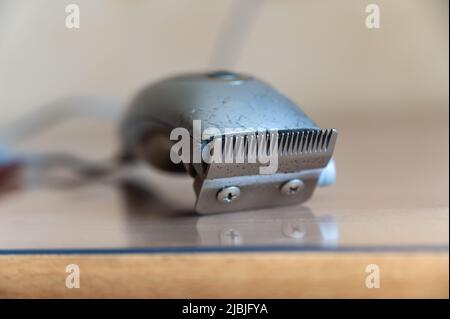 The hair clipper lies on the beige table. The gray body of the device ...