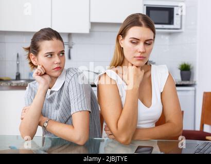 Two angry friends after a quarrel sitting on a couch and looking at the ...