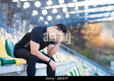 Upset Young male runner resting leaning against wall Stock Photo - Alamy
