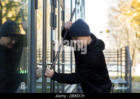 Asian man robber tries to break the door lock with a large metal ...