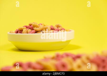 Quick cereal breakfast in the form of rings on a plate on a yellow ...
