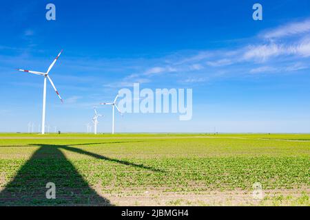 Long shadow under wind generator, turbines, with rotating blades ...
