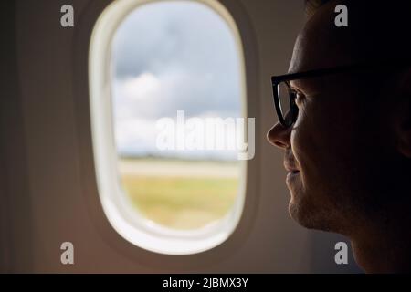 Portrait of man traveling by airplane. Passenger looking through plane ...