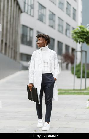 Portrait of African young IT specialist with folder smiling at camera ...