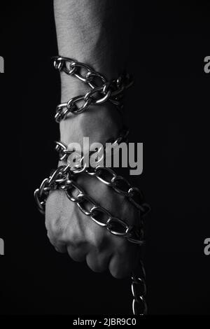 Mans hand entangled with a metal chain, concept slavery, hostage and ...