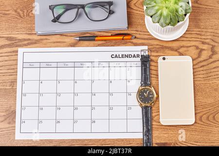 Calendar with smartphone pen and watch clock on brown wooden desk ...