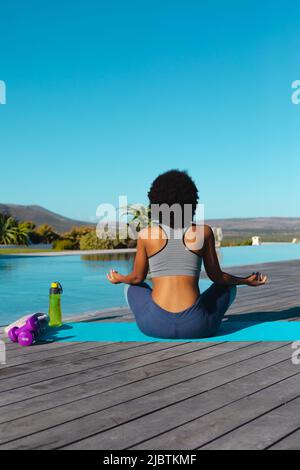 Rear view of african american woman practicing yoga and meditating near ...