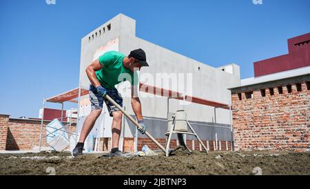 Workman shoveling sand into a Cement Mixer Stock Photo - Alamy