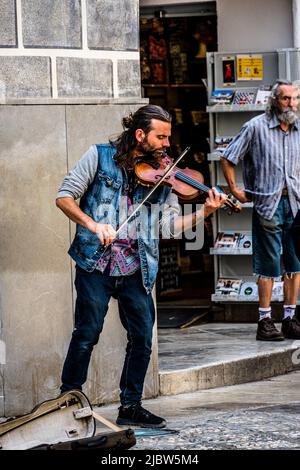 A street musician plays the violin on a sidewalk in northern Tehran ...