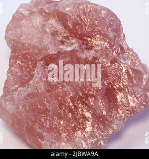 Several pieces of polished pink quartz on white textured fabric ...