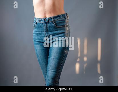 Slender female hips in blue jeans. Hands on hips. Stretch marks on skin ...
