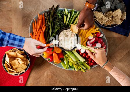 Three people dipping in to veggie platter Stock Photo - Alamy