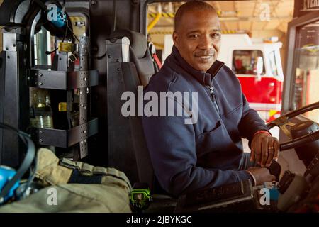 Portrait of Fireman Sitting in Drivers seat of firetruck looking ...