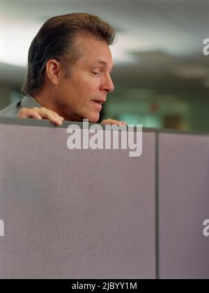 Businessman peeking over cubicle wall Stock Photo - Alamy