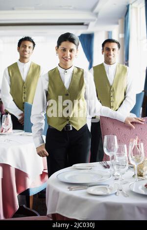 Professional waiters in uniform setting the dining table with plates ...