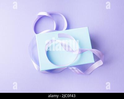 Wrapping blue pastel present box with ribbon on purple background Stock ...