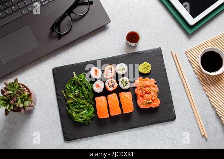 Sushi takeaway at work desk overhead. Eating sushi for lunch break ...