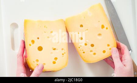 Flat lay. Slicing a large slice of gourmet cheese on a white background ...