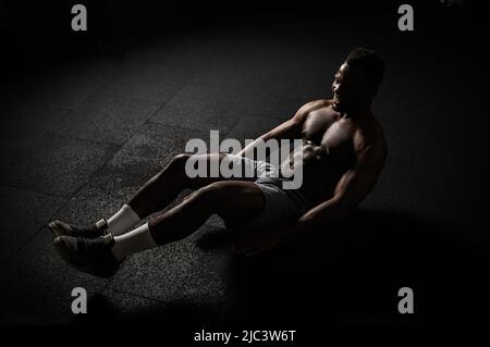 Afro american man doing abdominal exercises in a dark studio Stock ...