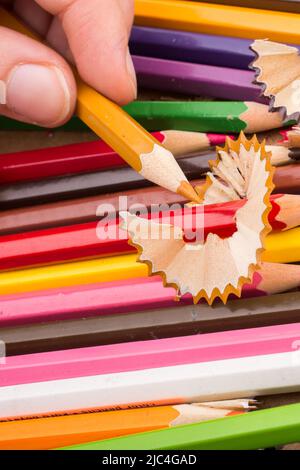 Hand holding Color Pencil over a notebook with pencil shavings Stock ...