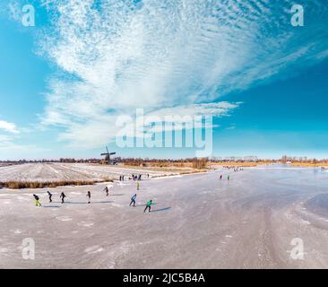 Scaters at a frozen-over Gouw with the windmills Het Prinsenhof ...
