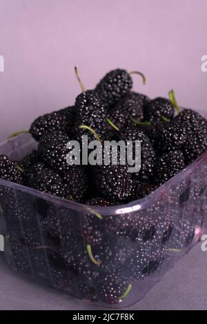 Closeup of ripe dark mulberries in brushed gold bowl. Soft natural ...