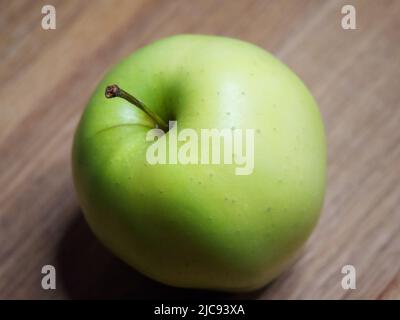 One apple of Golden cultivar on a wooden surface. Close-up shot Stock ...