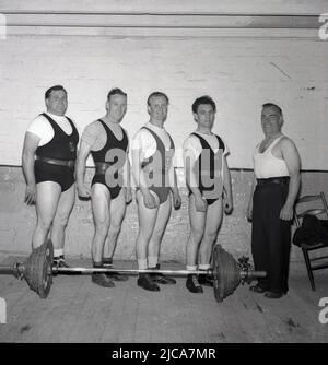 1957, historical, weight-lifting, inside a gym on a wooden board, a ...