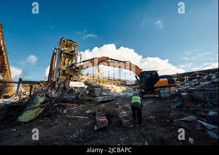 Excavator destroyer removes debris under worker control Stock Photo - Alamy