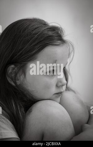 portrait of little sad shocked wounded girl sitting, hugging knees ...